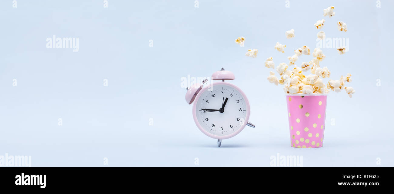 Flying Popcorn in a bright glass and a ringing alarm clock on a blue ...