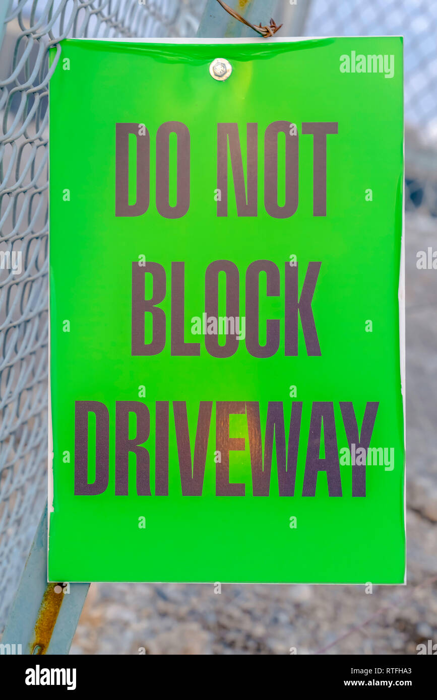 Do Not Block Driveway sign on a mesh wire fence. Close up view of a ...