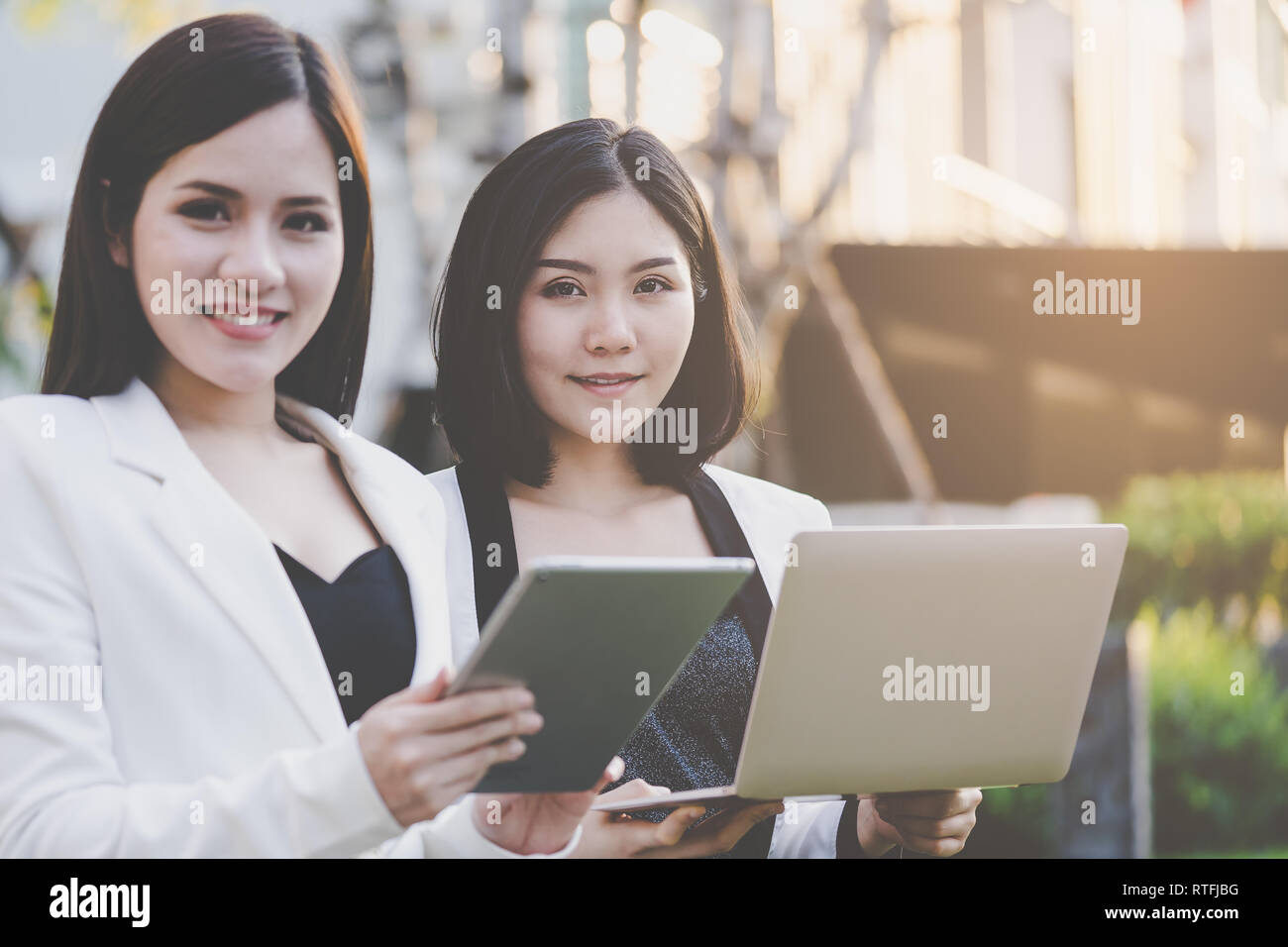 Two business woman holding laptop and tablet Stock Photo - Alamy