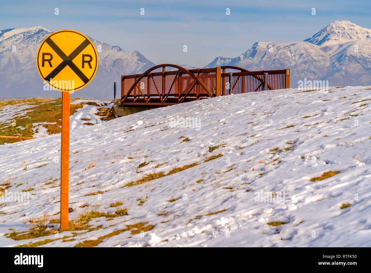 Railway sign against a bridge and snowy mountain. Railroad Crossing ...
