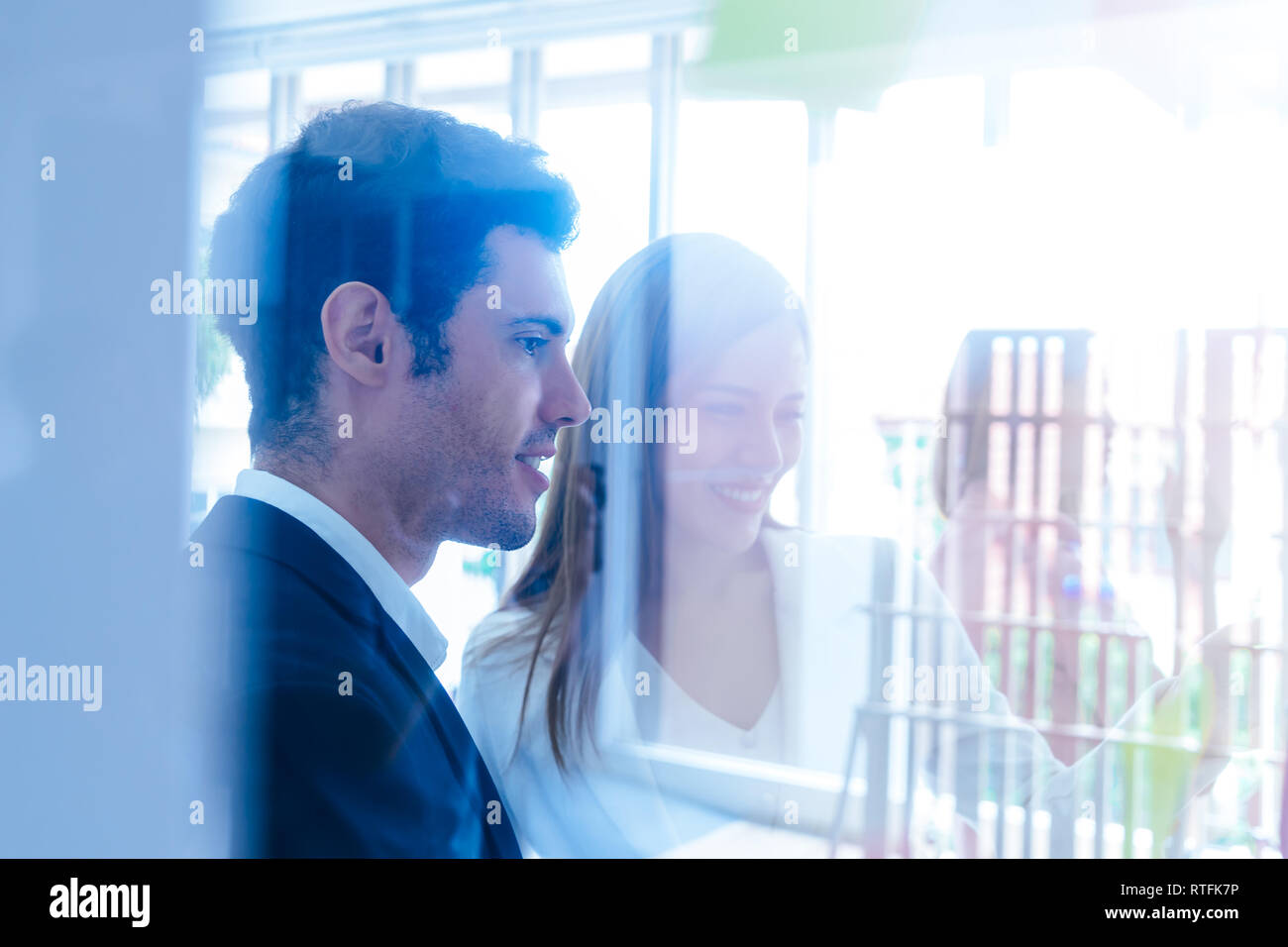 Three Business people is writing idea on to post it windows for team ...