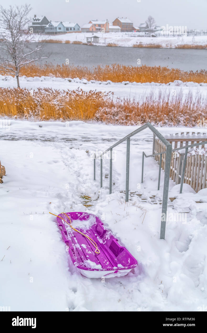Sled on snow with lake and homes in the background. Snow covered ...