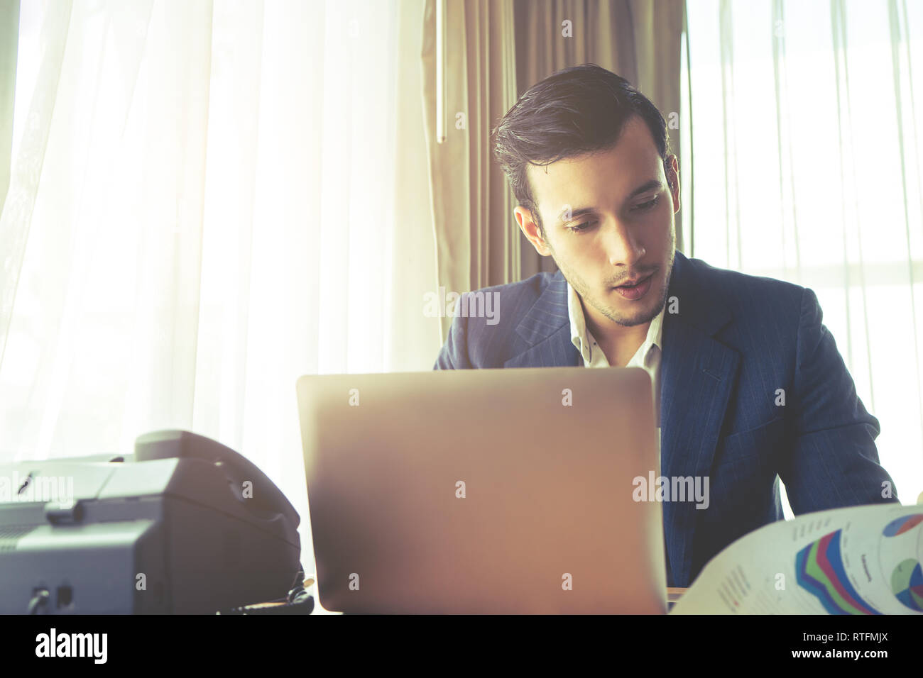 Business man is working on laptop on office desk with light shining in ...