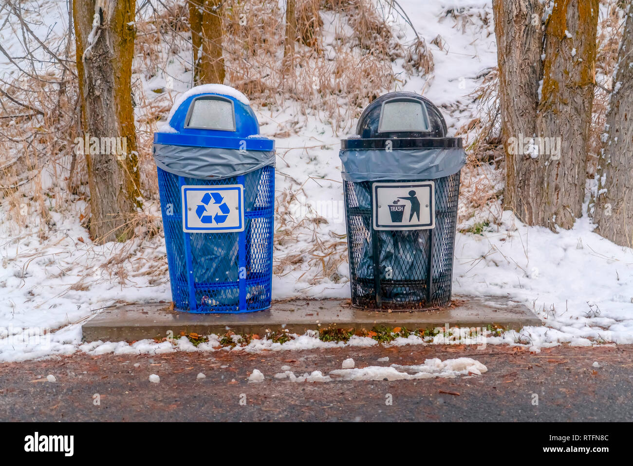 Trash cans with snowy slope and trees background. A blue and black ...