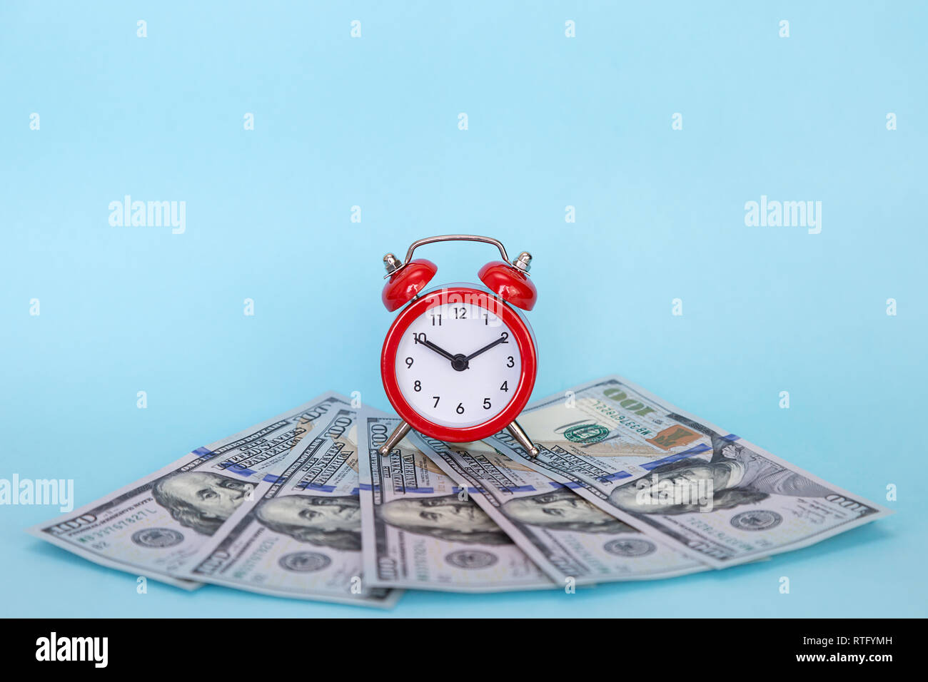 Red retro alarm clock and dollars on a colored background. Concept ...