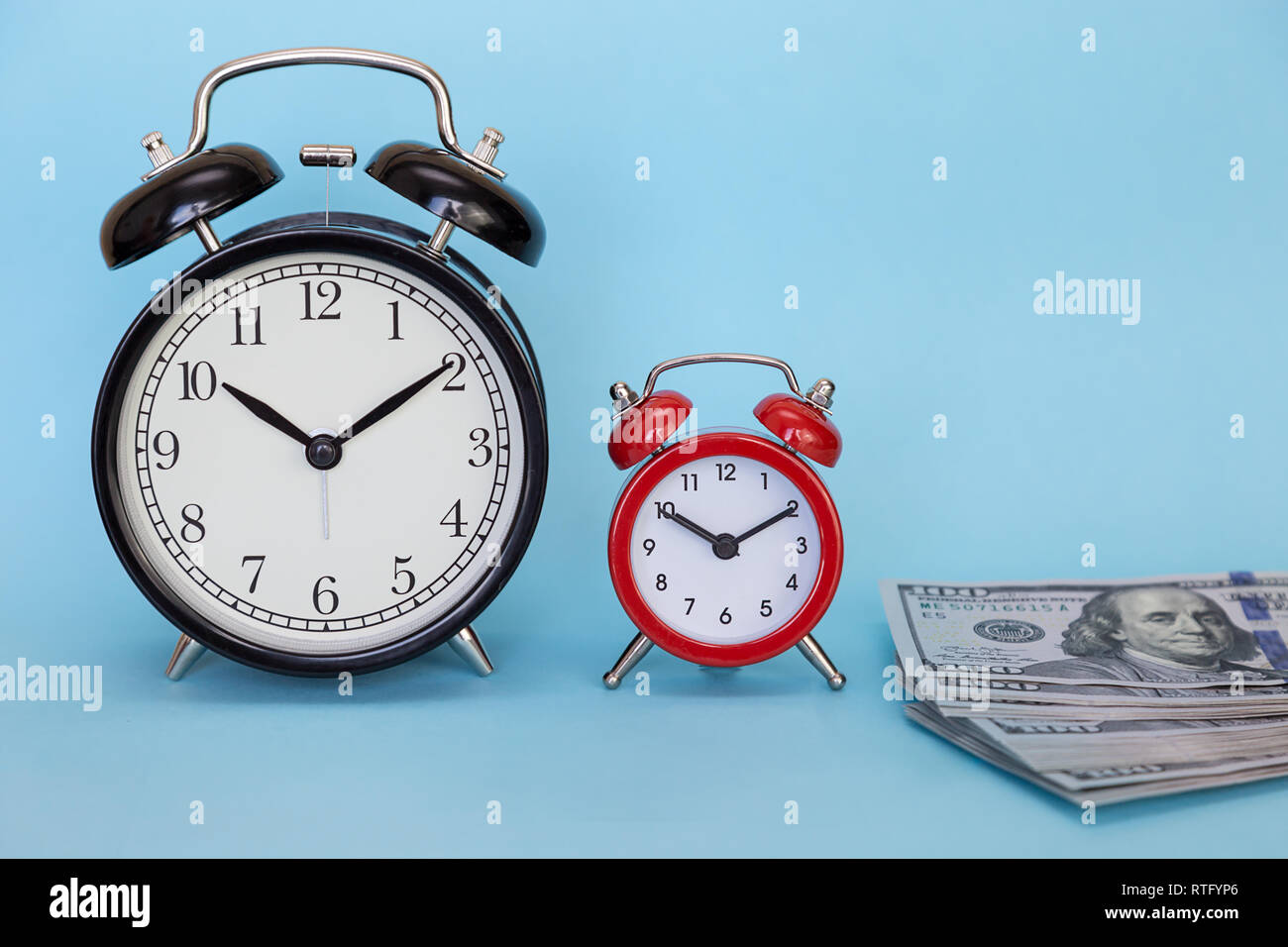 Two retro alarm clock and dollars on a blue background. Concept - time ...