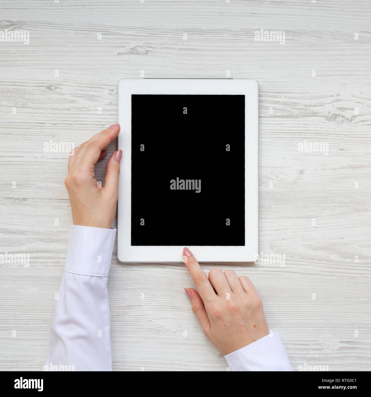 Top view, female hands using tablet on a white wooden background. From ...