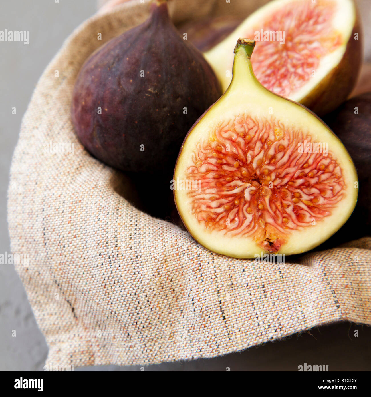Fresh figs in a bowl over concrete background, side view. Close-up ...