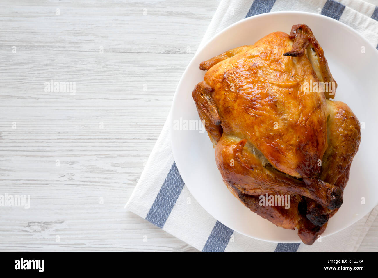 Homemade tasty rotisserie chicken on white plate, top view. Flat lay ...