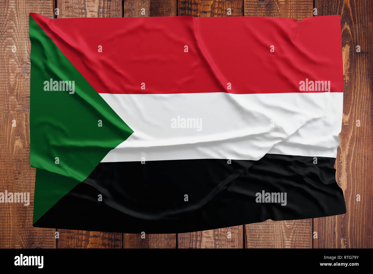 Flag of Sudan on a wooden table background. Wrinkled Sudanese flag top ...
