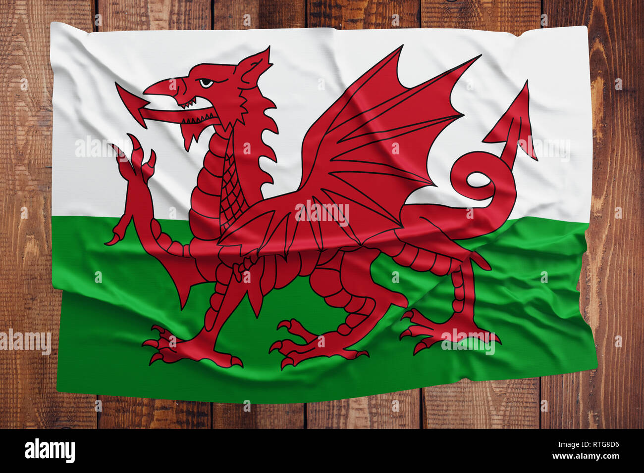 Flag of Wales on a wooden table background. Wrinkled Galler flag top ...