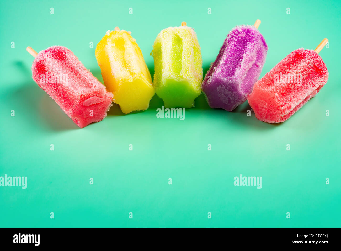 side view multi-color popsicles line up on green background with copy ...