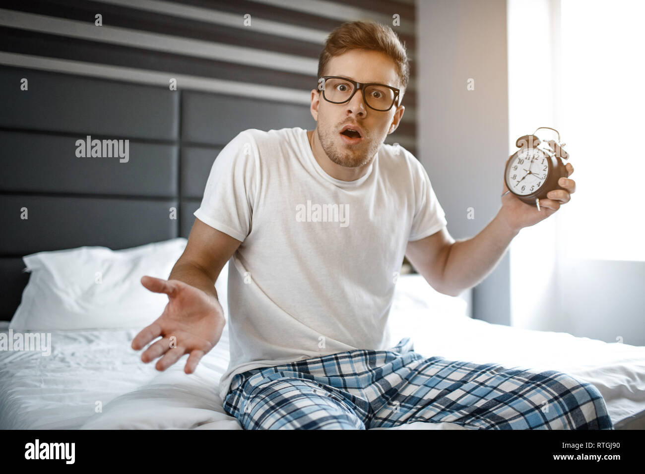 Amazed scared young man on bed this morning. He look on camera and hold ...