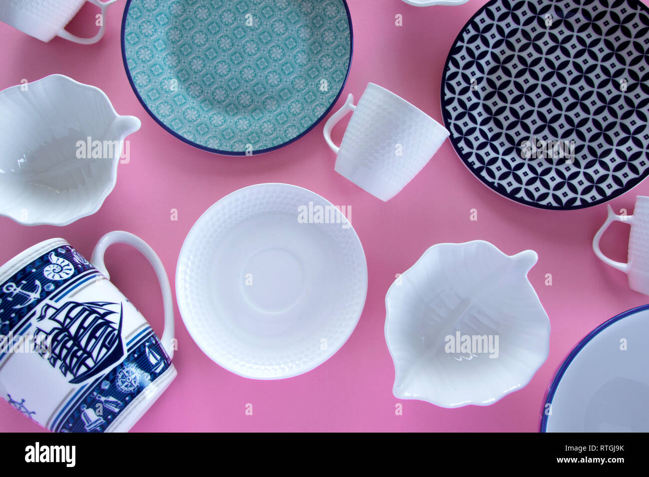 Overhead flat lay view of different clean tableware on pink background ...