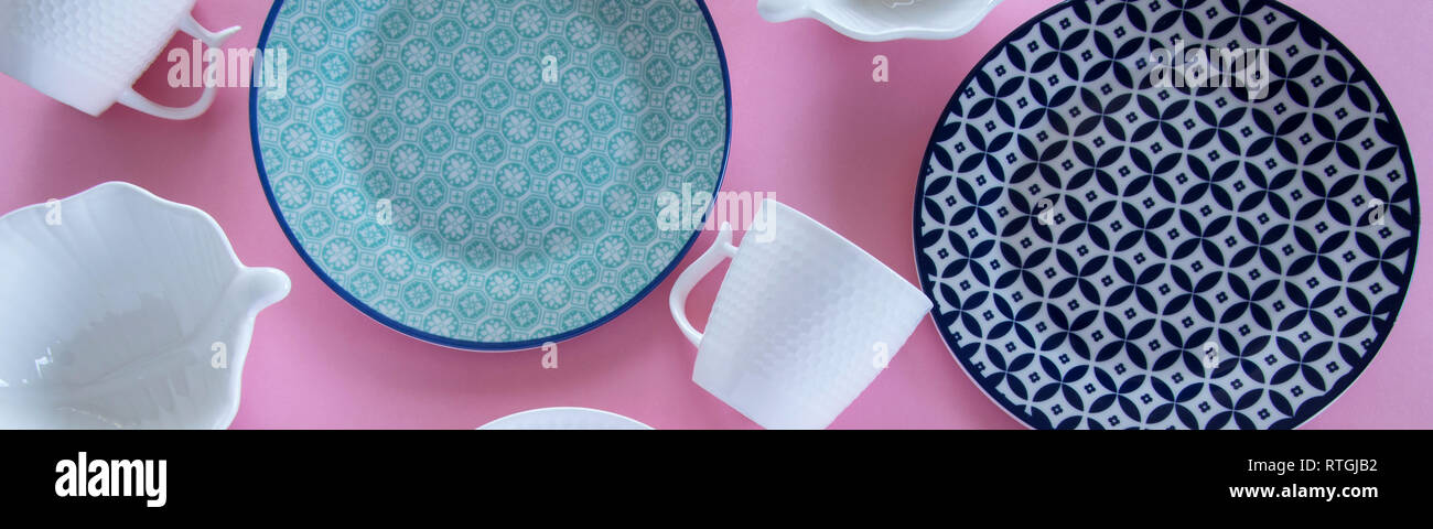 Overhead flat lay view of different clean tableware on pink background ...