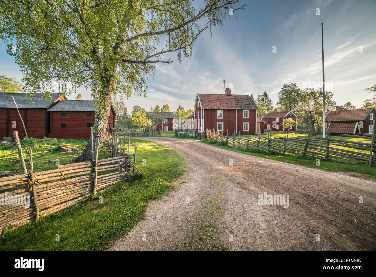 Small road and old cottages by traditional roundpole fence in a rural ...