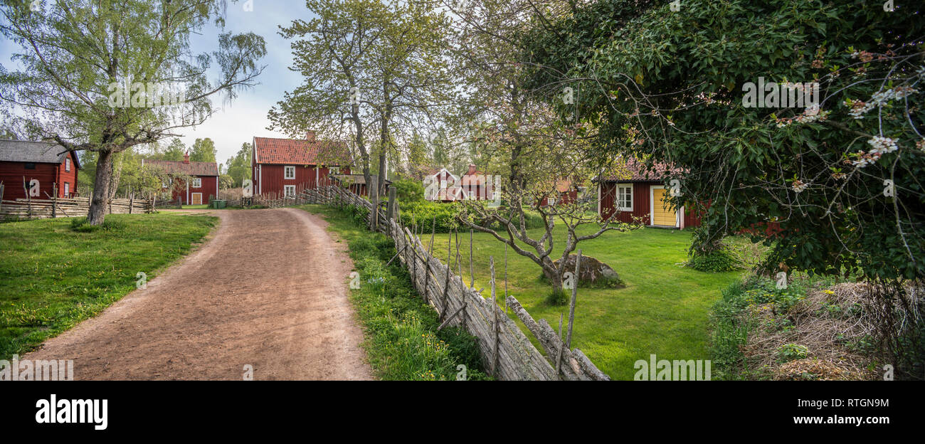 Small road and old cottages by traditional roundpole fence in a rural ...
