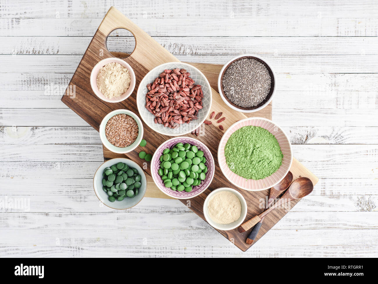 Different super foods in bowls on white wooden background, top view ...