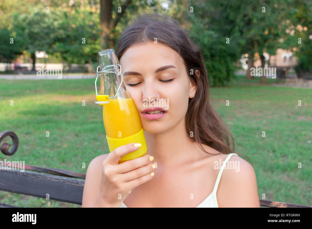 Young woman is tired of hot weather. Girl is holding a cold bottle of ...