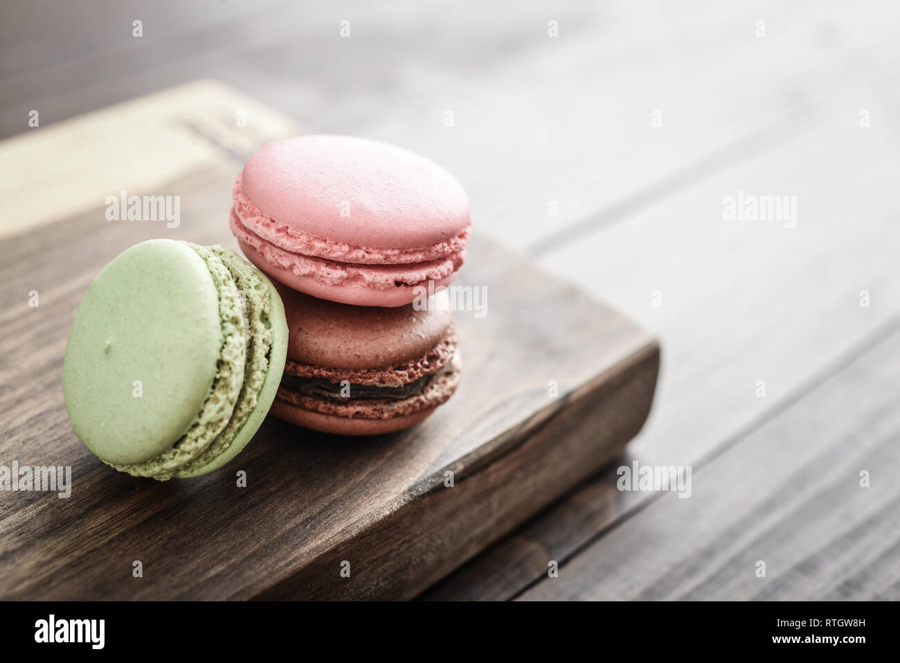 Different kinds of macaroons in stack on wooden background closeup ...