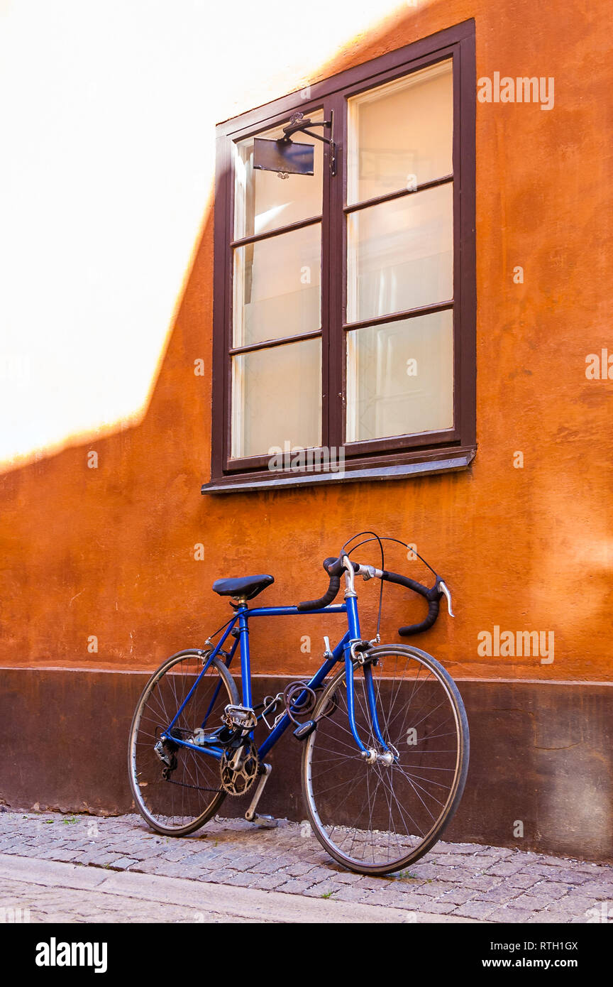 Blue sport bicycle standing near the vibrant orange building facade ...