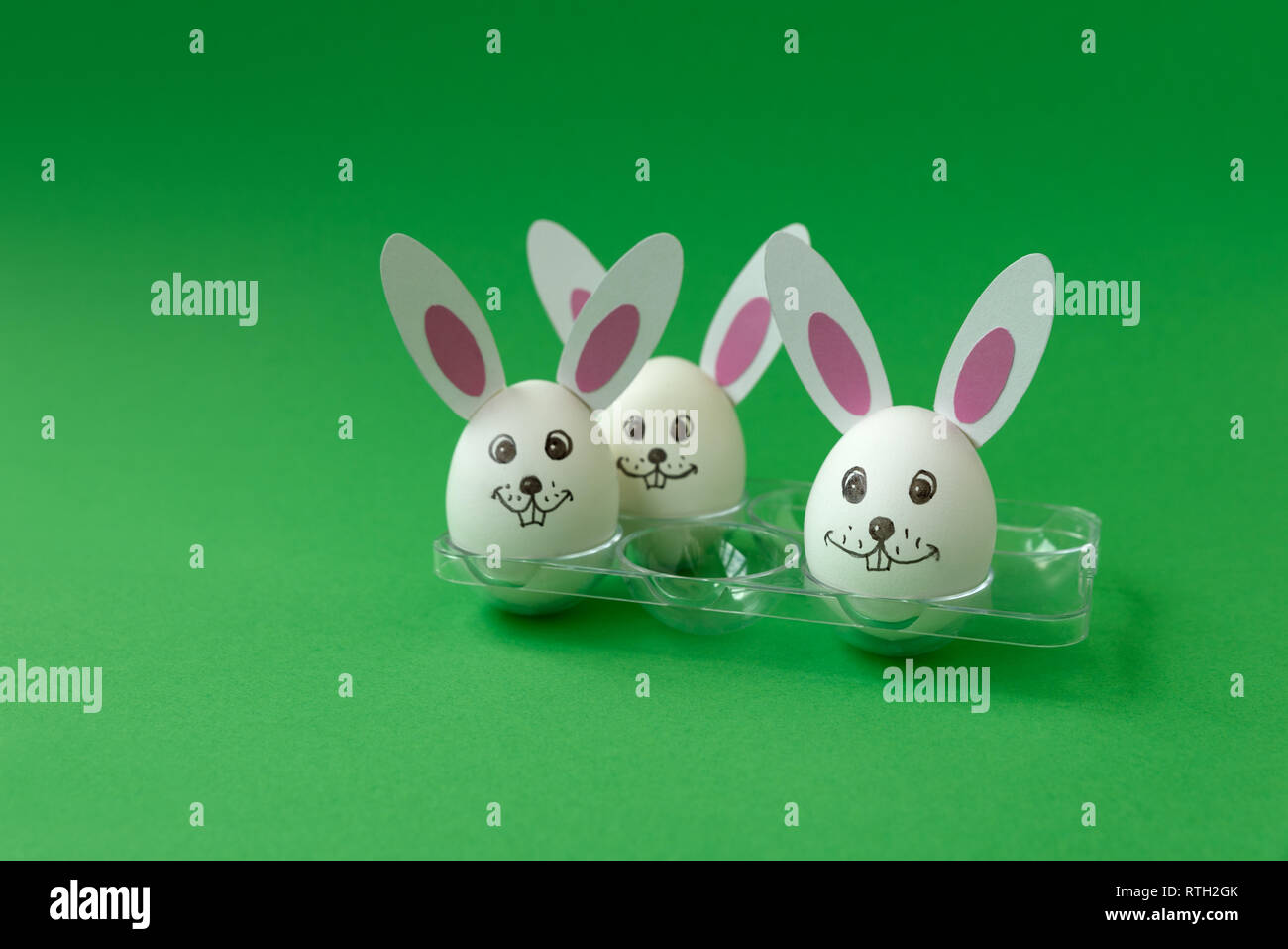 Busket with Easter bunny made from eggs and paper ears on green pastel ...