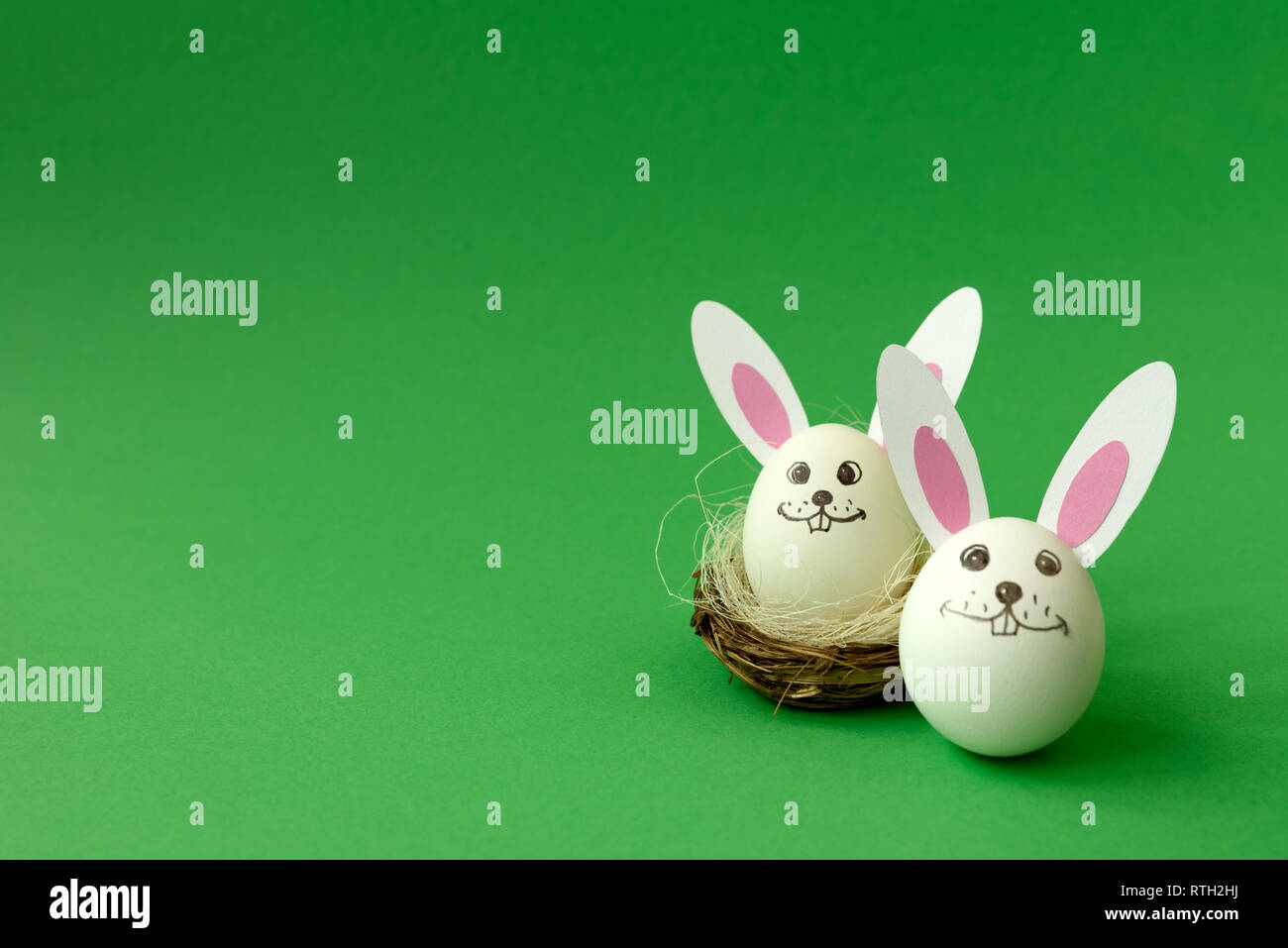 Busket with Easter bunny made from eggs and paper ears on green pastel ...