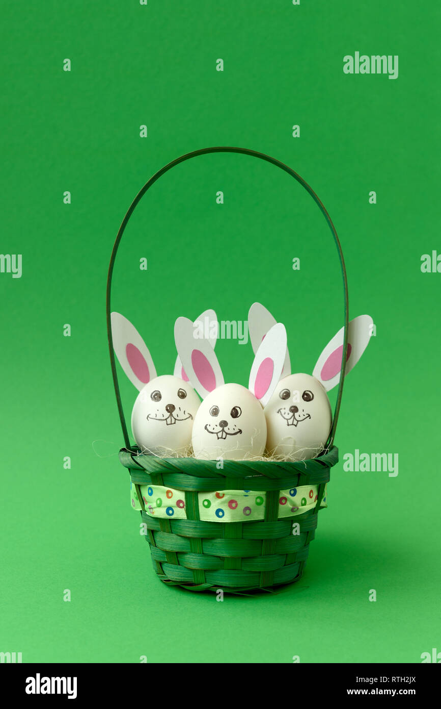 Busket with Easter bunny made from eggs and paper ears on green pastel ...