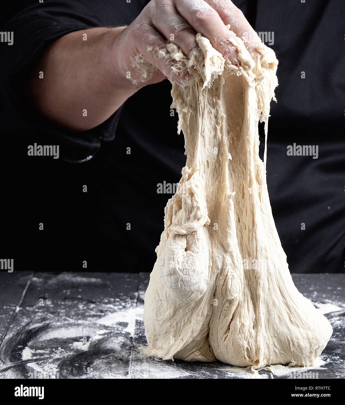 chef in black uniform kneads white wheat flour dough on the table Stock ...