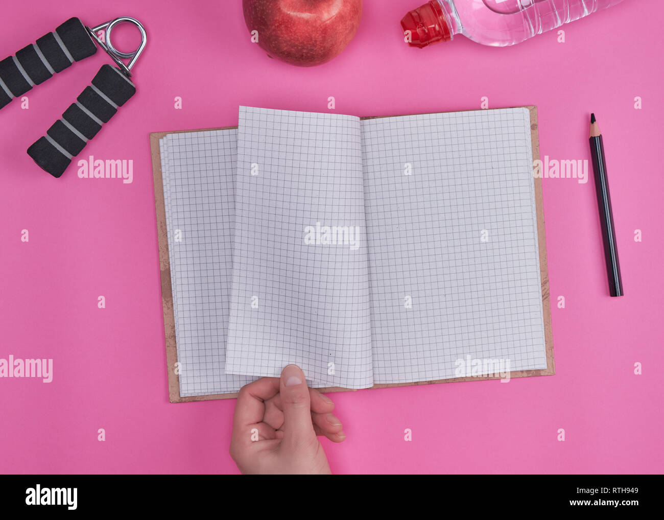 human hand turns over a notebook with empty sheets on a pink background ...