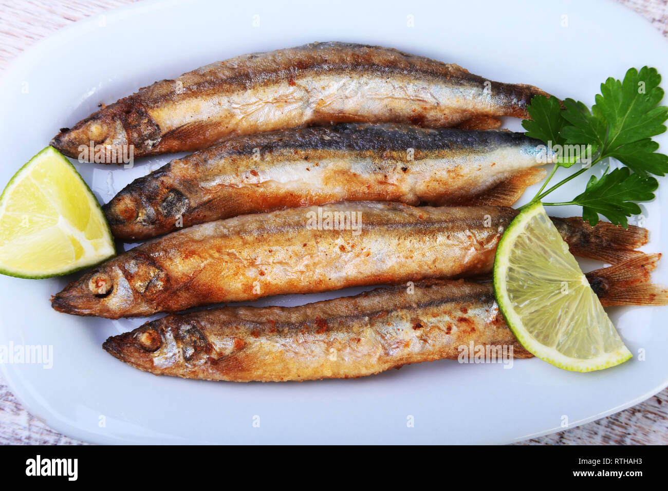 Deep frying small fish capelin and sliced lemon on white plate. Good ...
