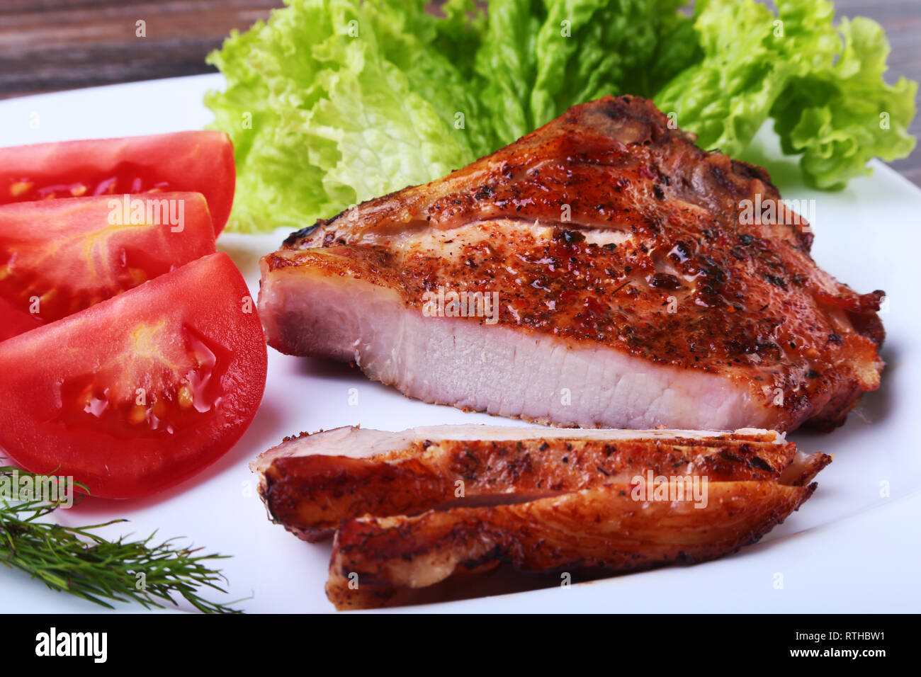 grilled pork chops with tomato, leaves lettuce and ketchup on plate ...