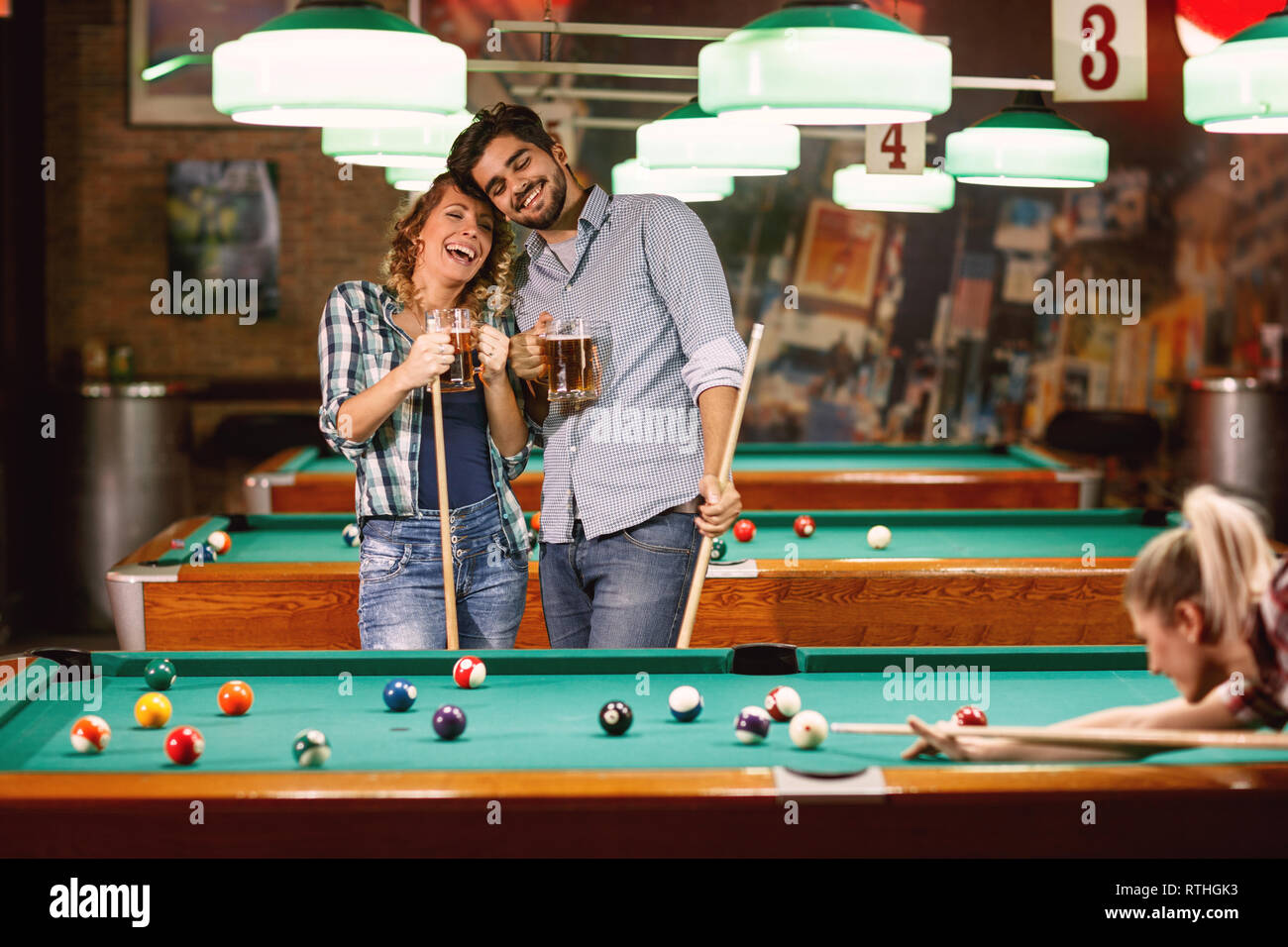 Friends enjoying playing billiard game in bar Stock Photo - Alamy
