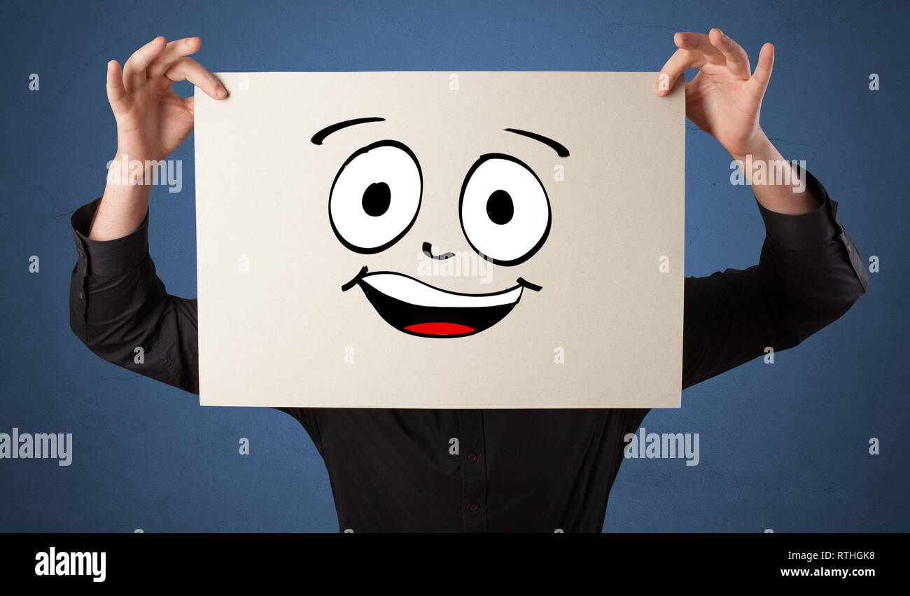 Young student holding a paper with laughing emoticon in front of his ...