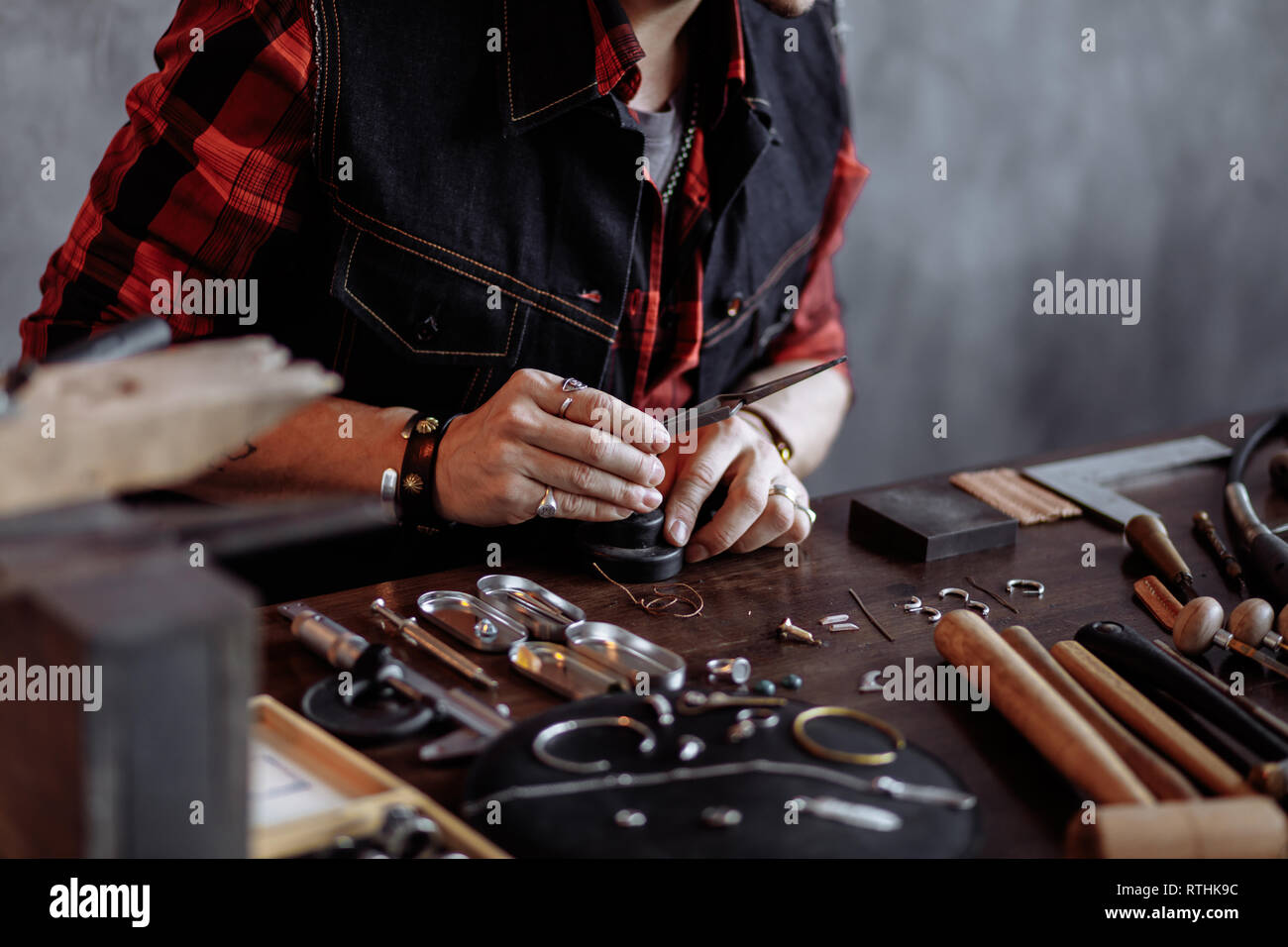 gorgeous creative man flattening and shaping metals and jewelries.close ...