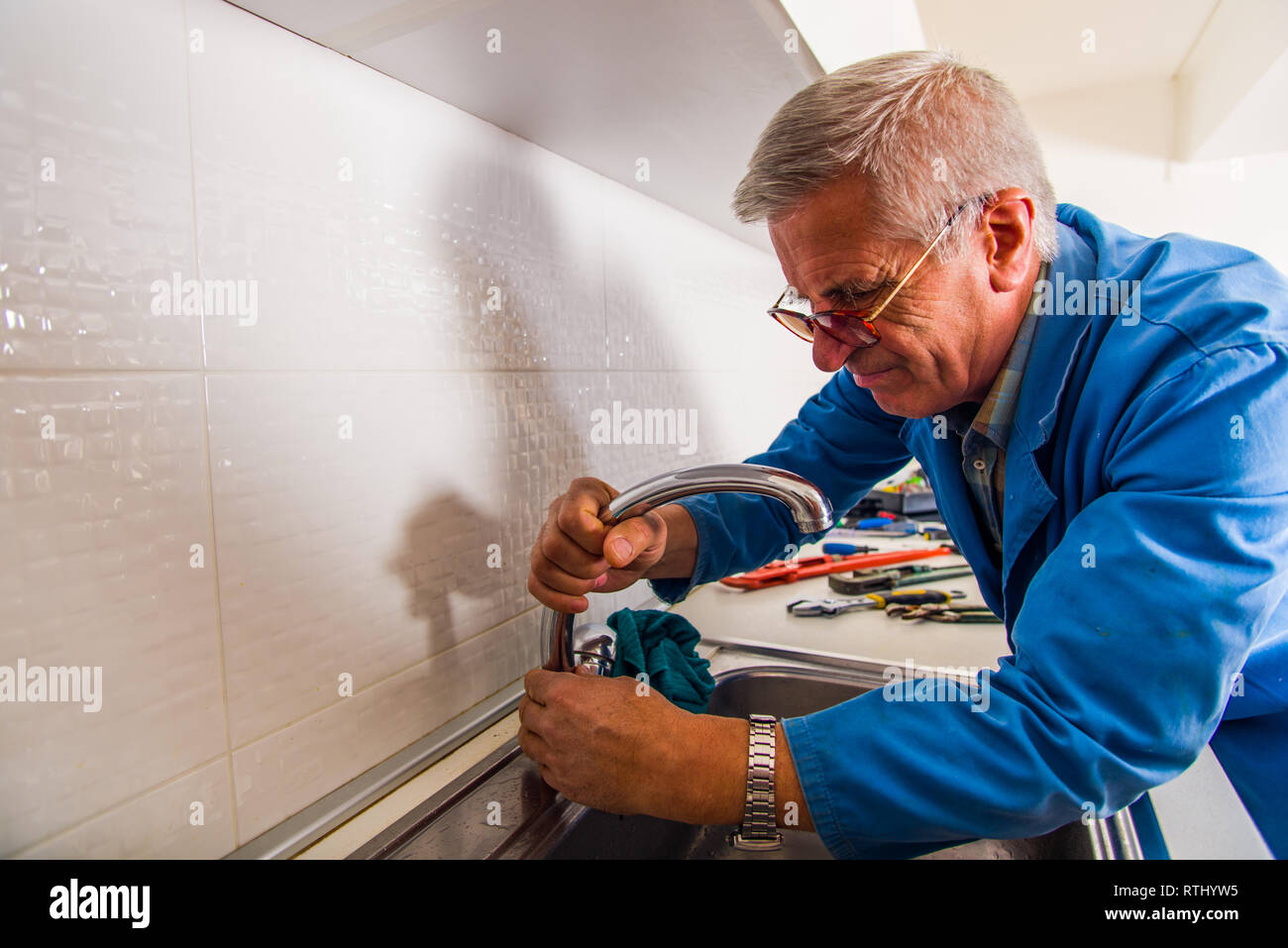 Professional male laborer wearing blue working suit is fixing the ...