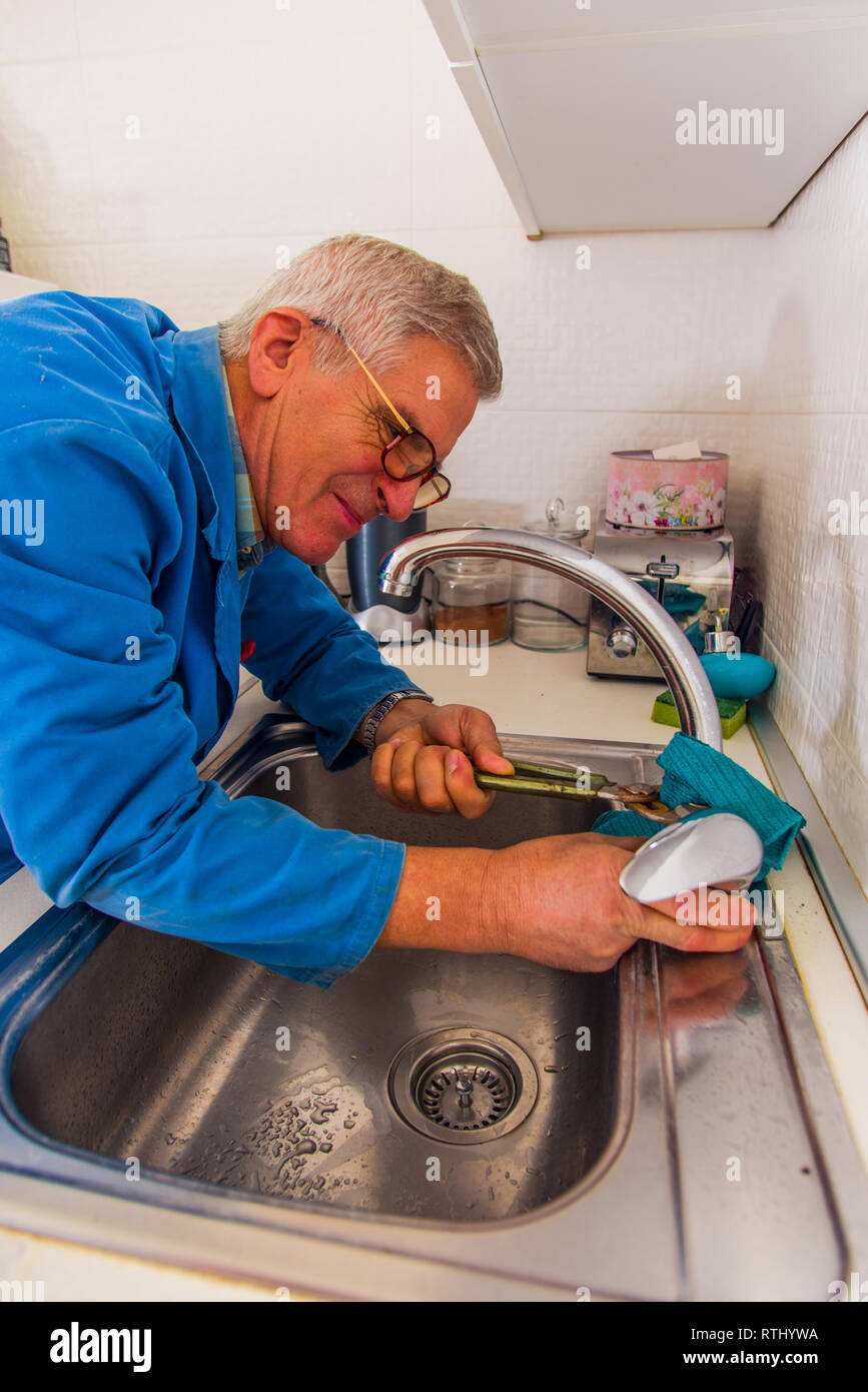 Angry repairman is fixing the kitchen faucet with wrench Stock Photo ...