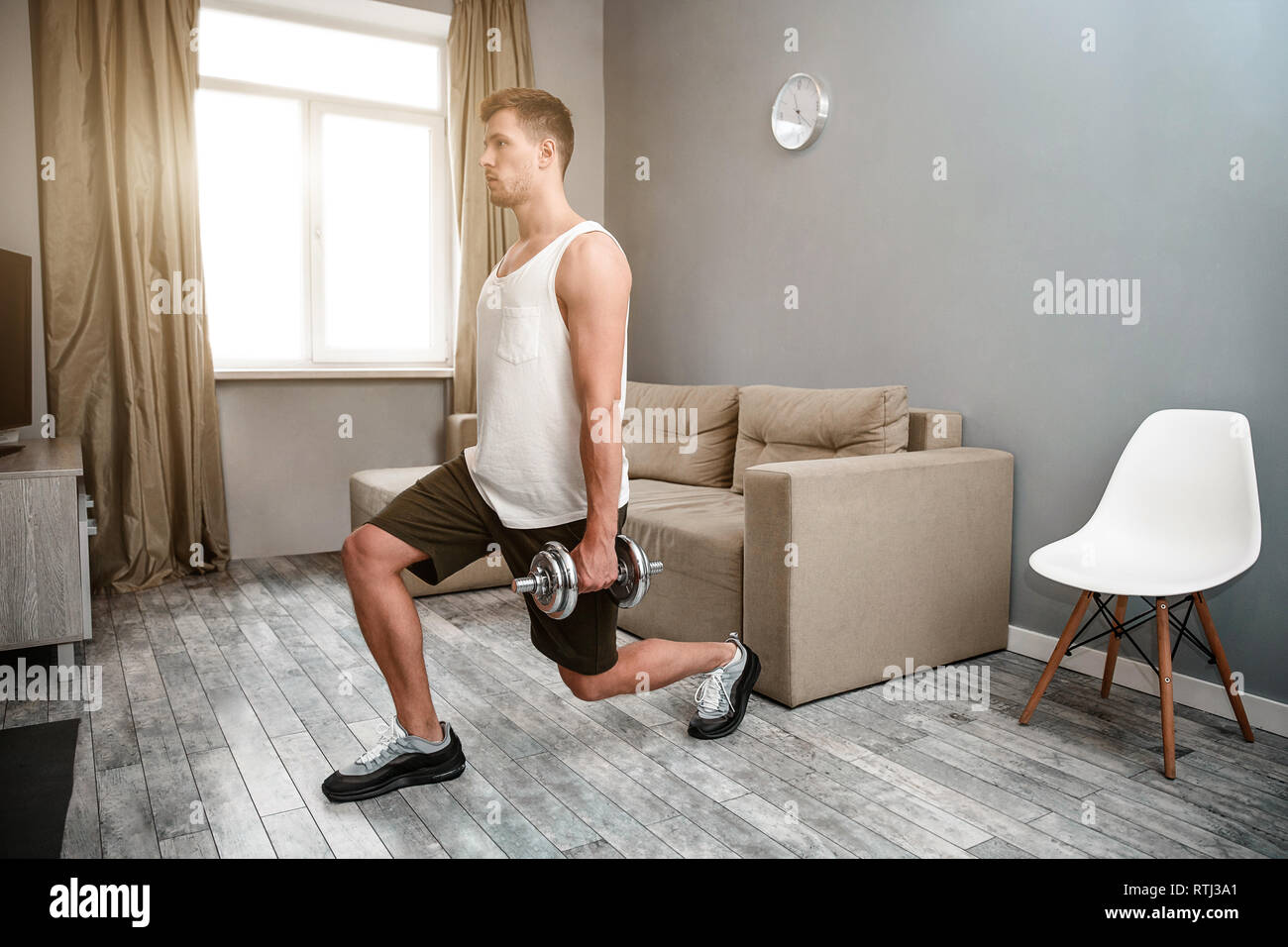 Young well-built man go in for sports in apartment. He does forward ...