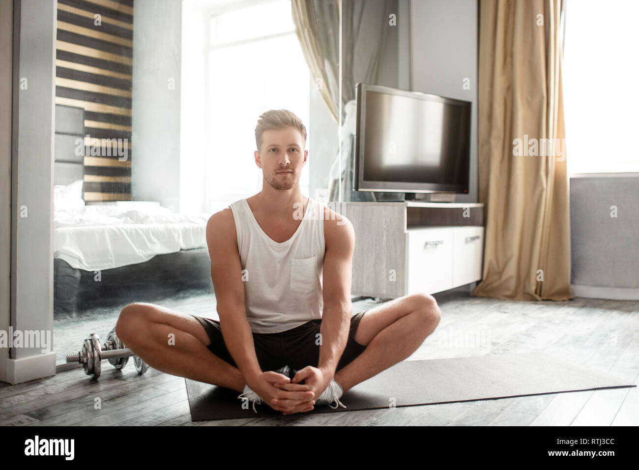Young well-built man go in for sports in apartment. Calm and peaceful ...