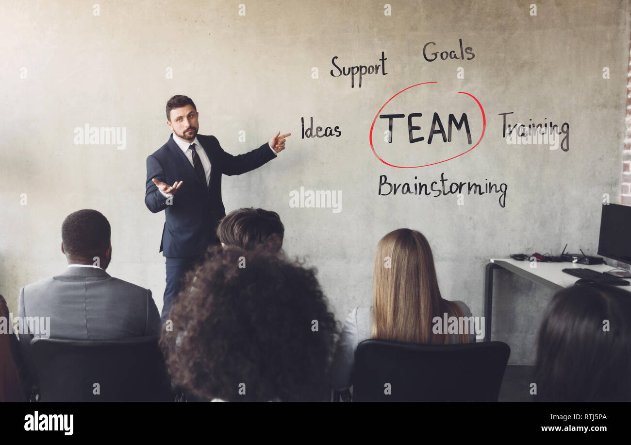 Business education seminar. Man showing teamwork components Stock Photo ...