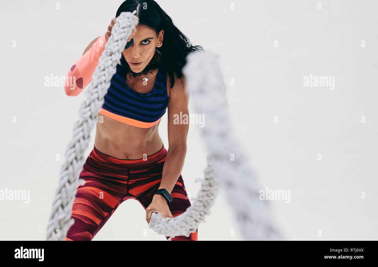 Athletic woman doing fitness training using battle ropes. Woman in ...