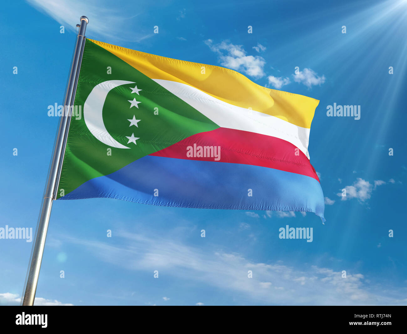 Comoros National Flag Waving on pole against sunny blue sky background ...