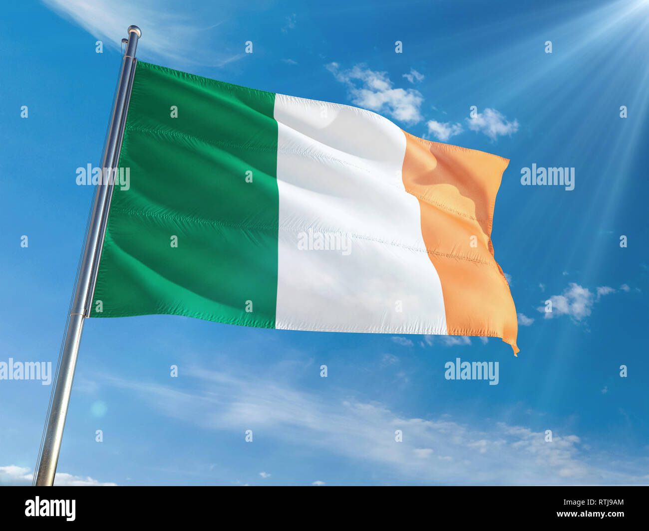 Ireland National Flag Waving on pole against sunny blue sky background ...