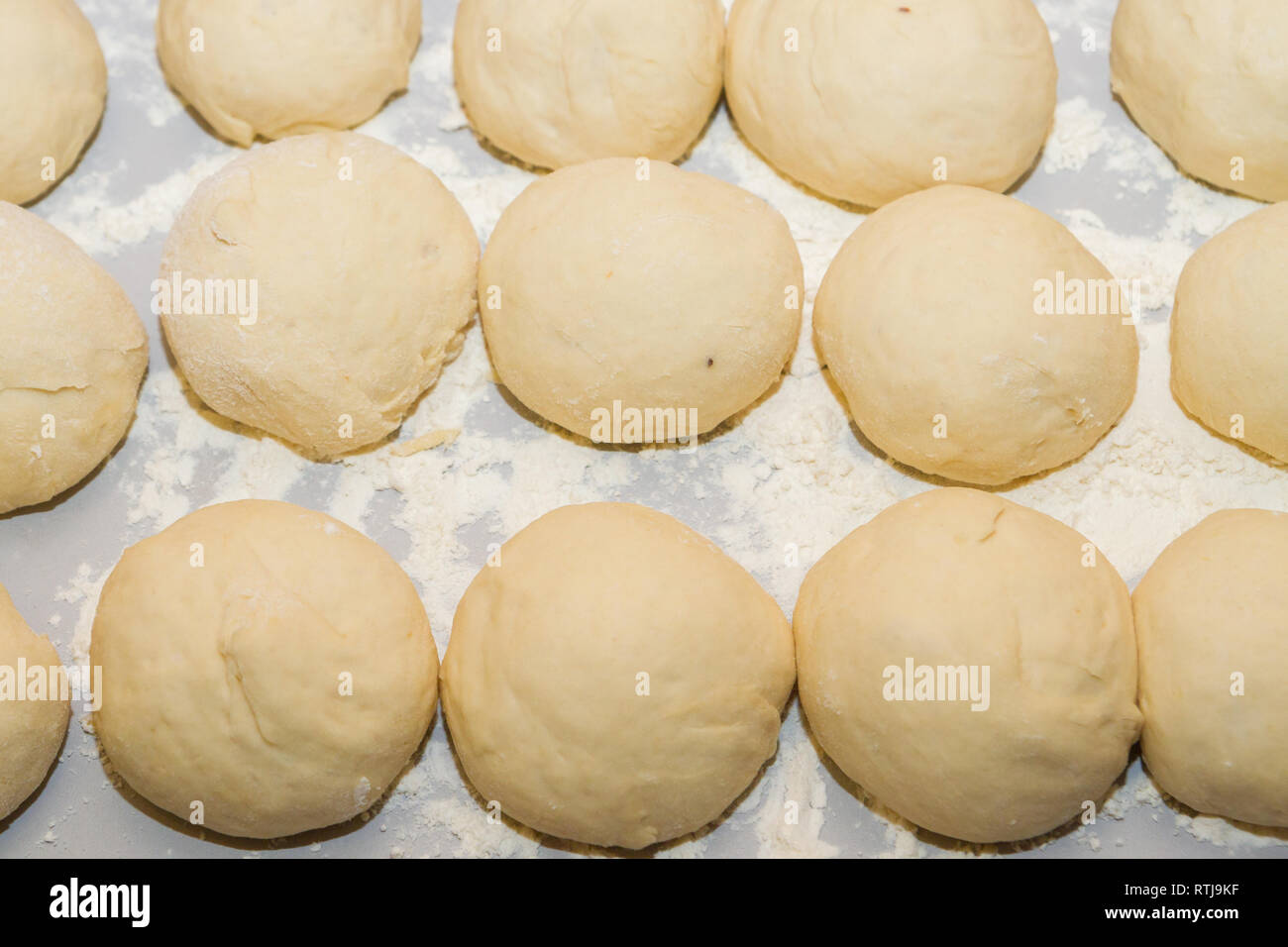 Raw dough rolled into balls is on the table rolled in flour Stock Photo ...