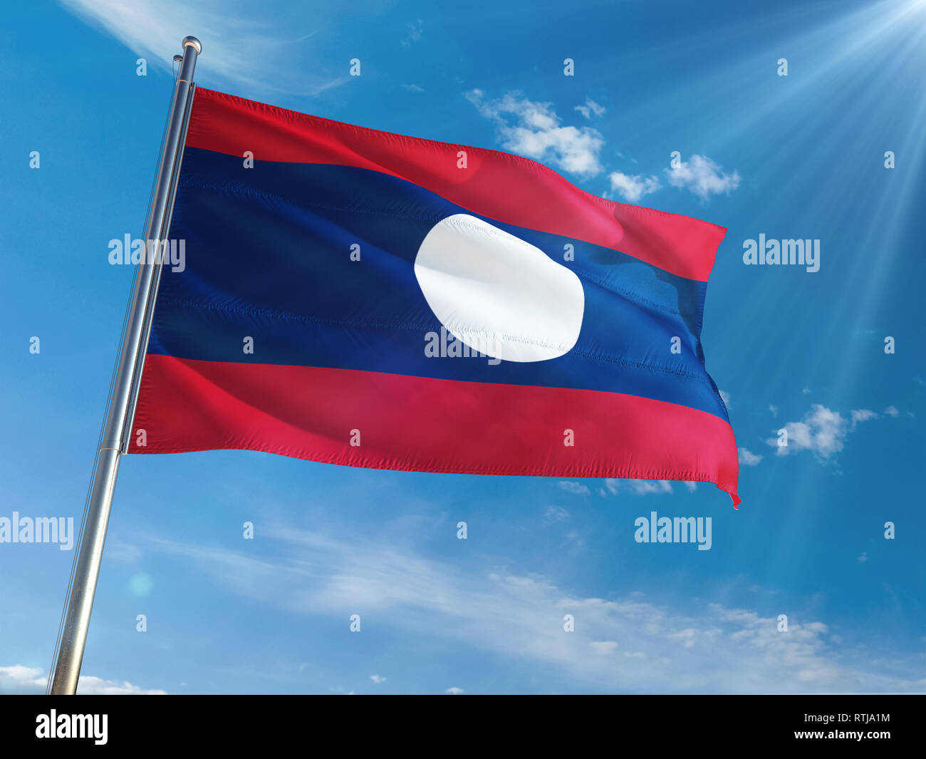 Laos National Flag Waving on pole against sunny blue sky background ...