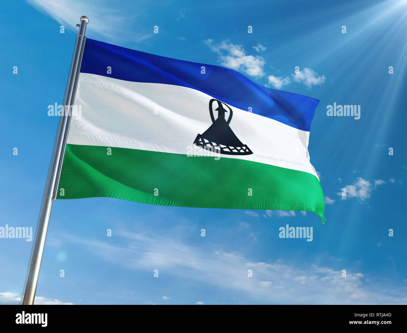Lesotho National Flag Waving on pole against sunny blue sky background ...