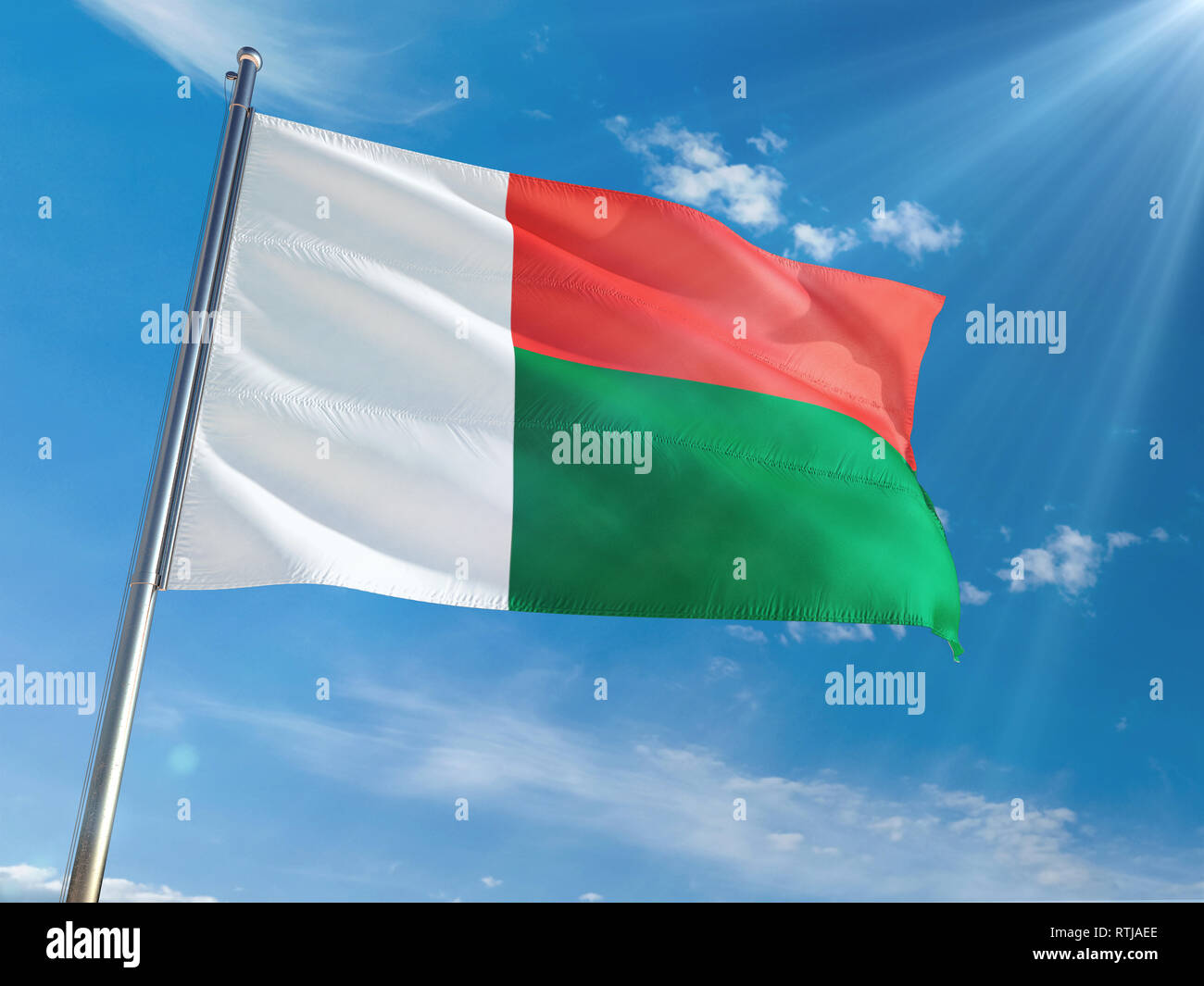 Madagascar National Flag Waving on pole against sunny blue sky ...