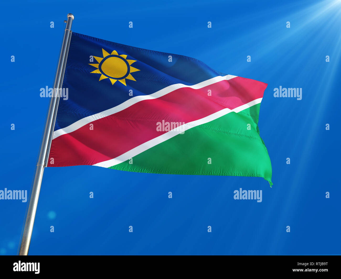 Namibia National Flag Waving on pole against deep blue sky background ...