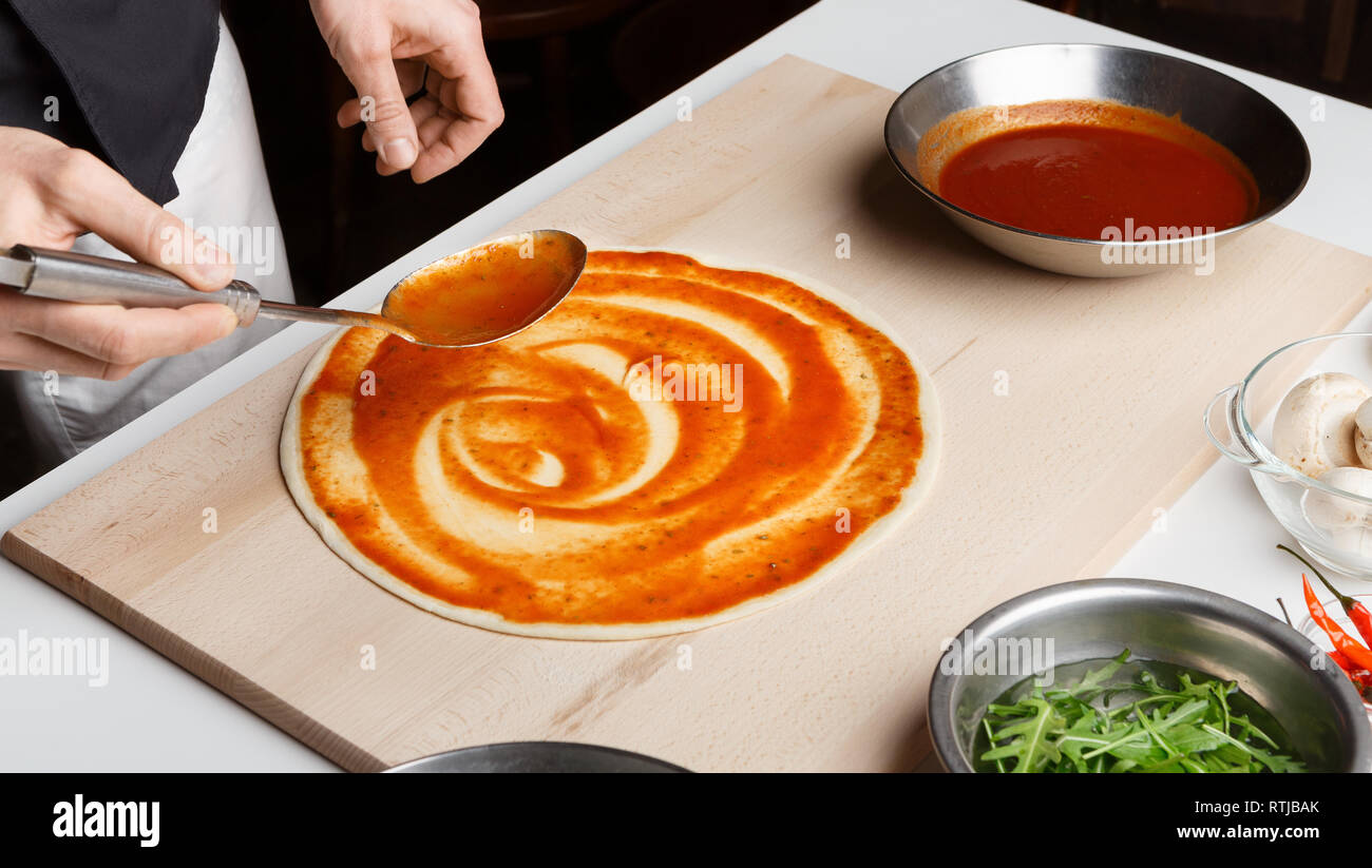 Adding sauce. Chef preparing italian pizza in restaurant Stock Photo ...