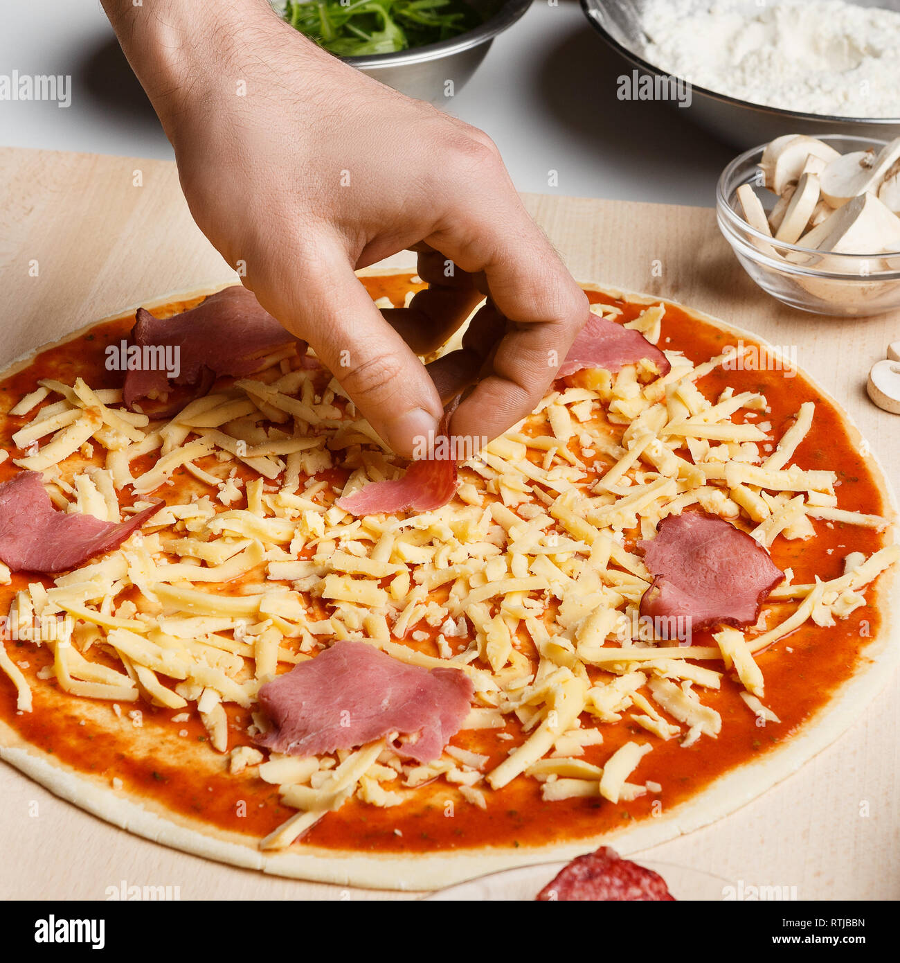Chef adding ingredients on the pizza, closeup Stock Photo - Alamy